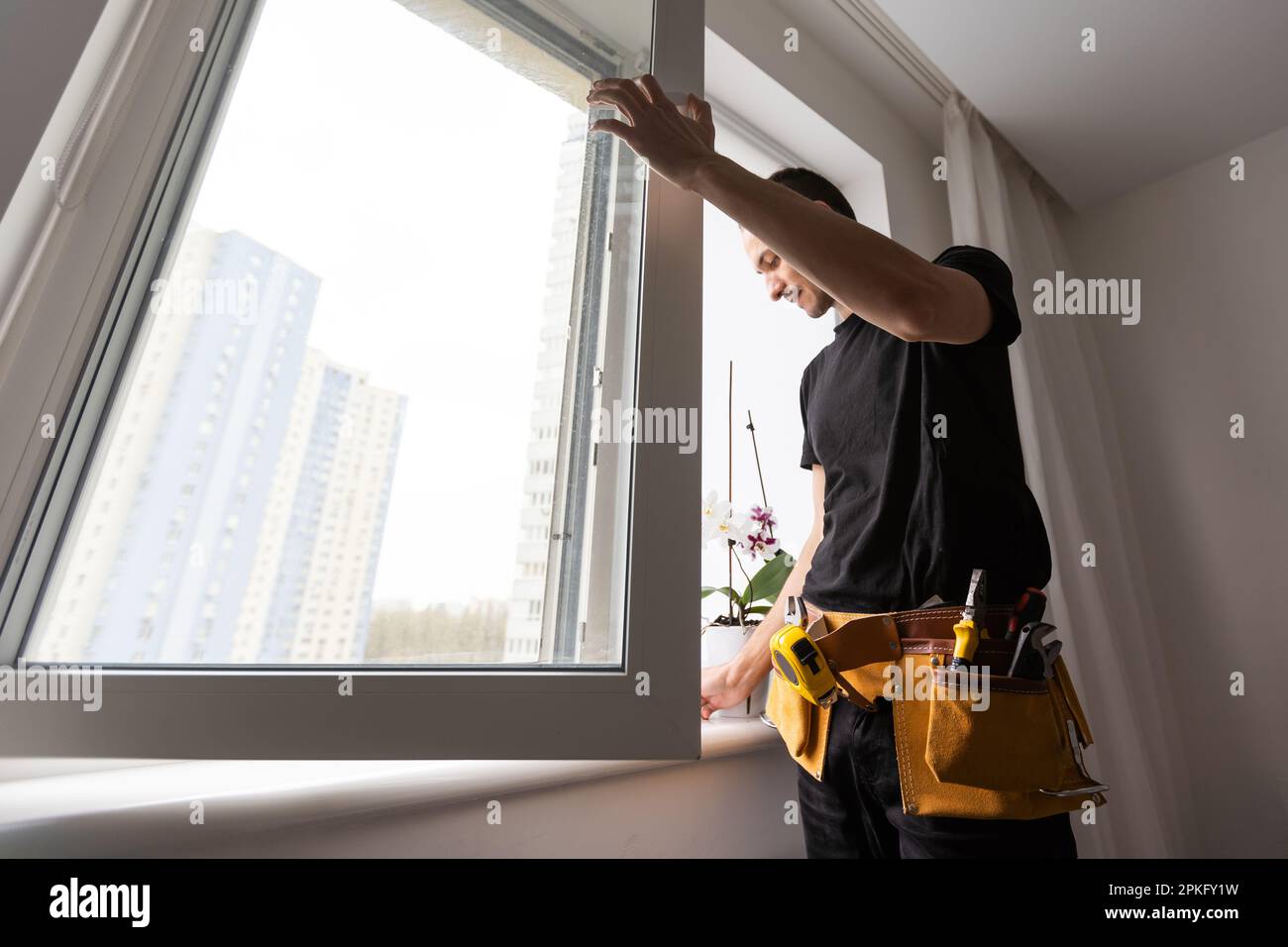 Young repairman fixing window frame in room at daytime Stock Photo - Alamy