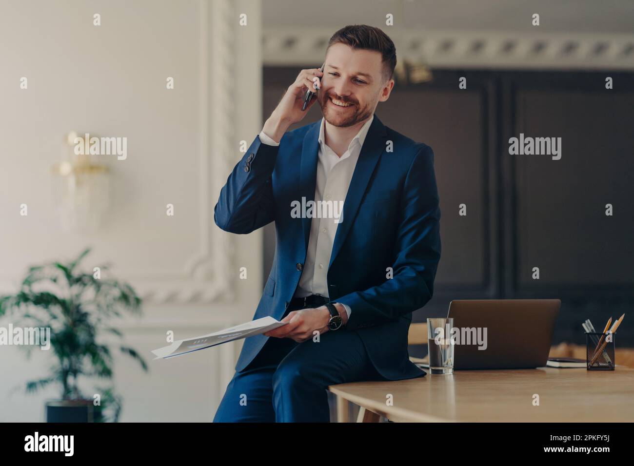 Indoor shot of positive entrepreneur dressed in formal suit has ...