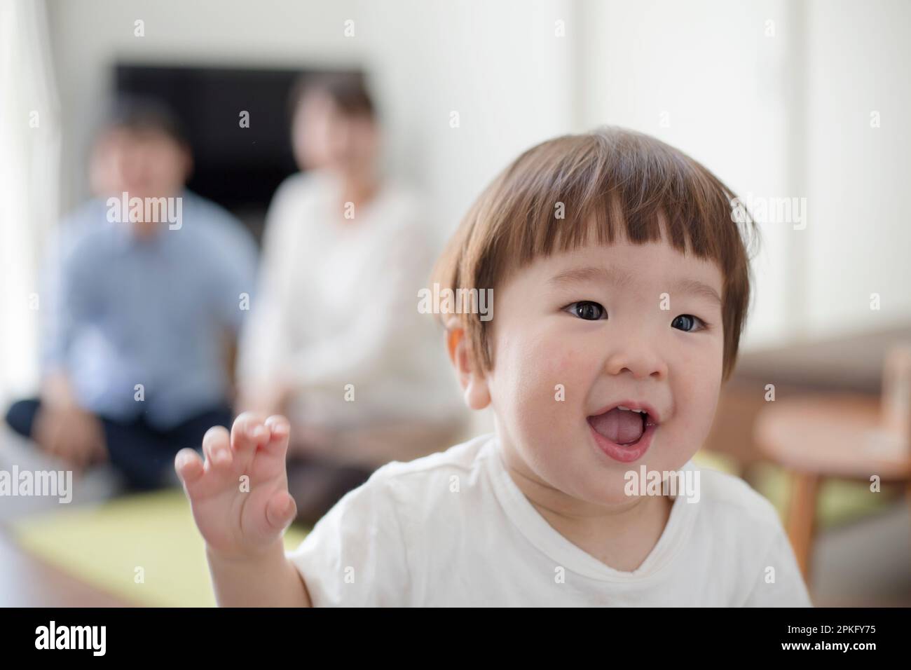 A baby walking in the living room with his mother and father watching over him Stock Photo - Alamy