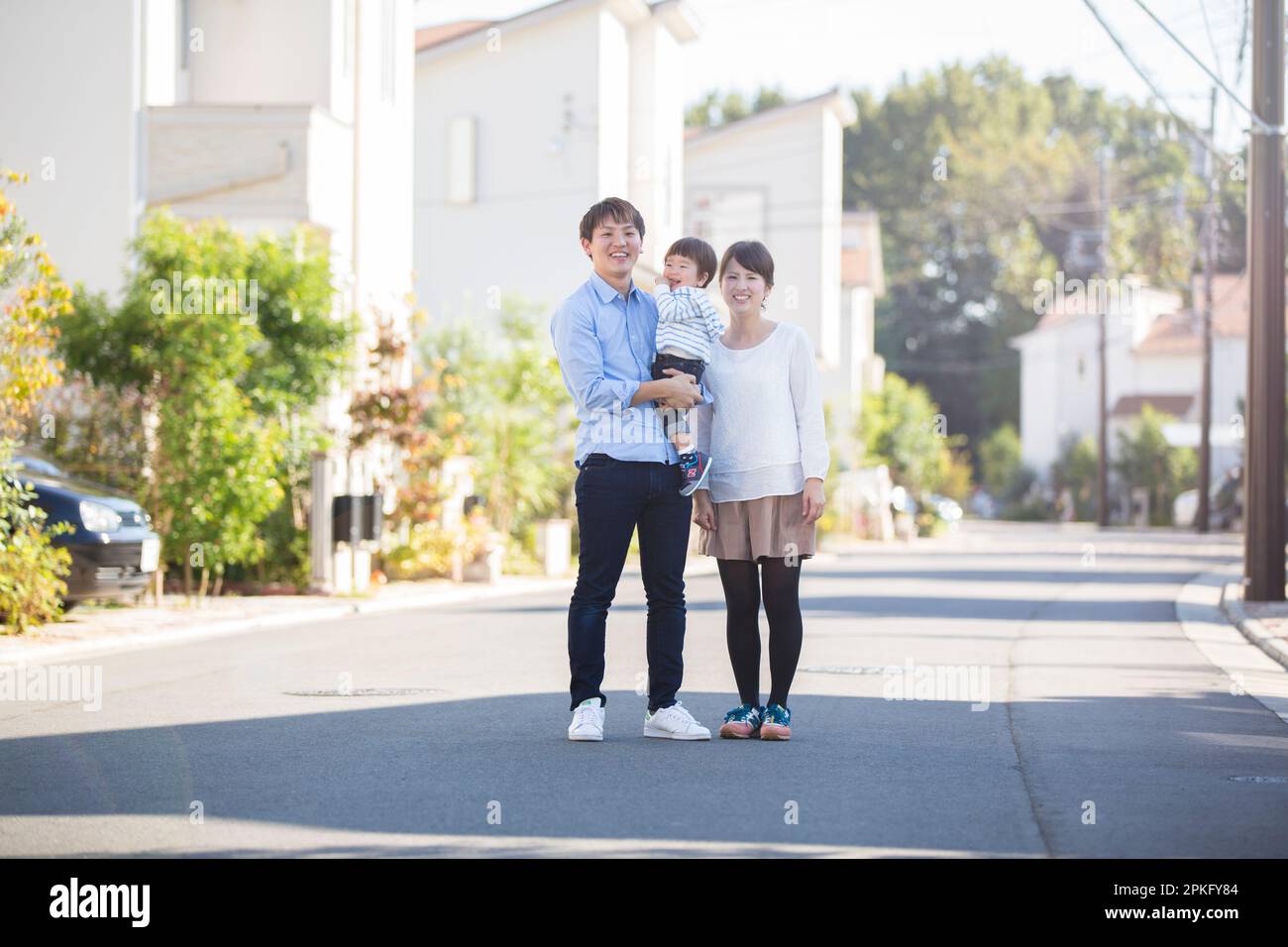 Smiling family standing on the street in front of their house Stock ...