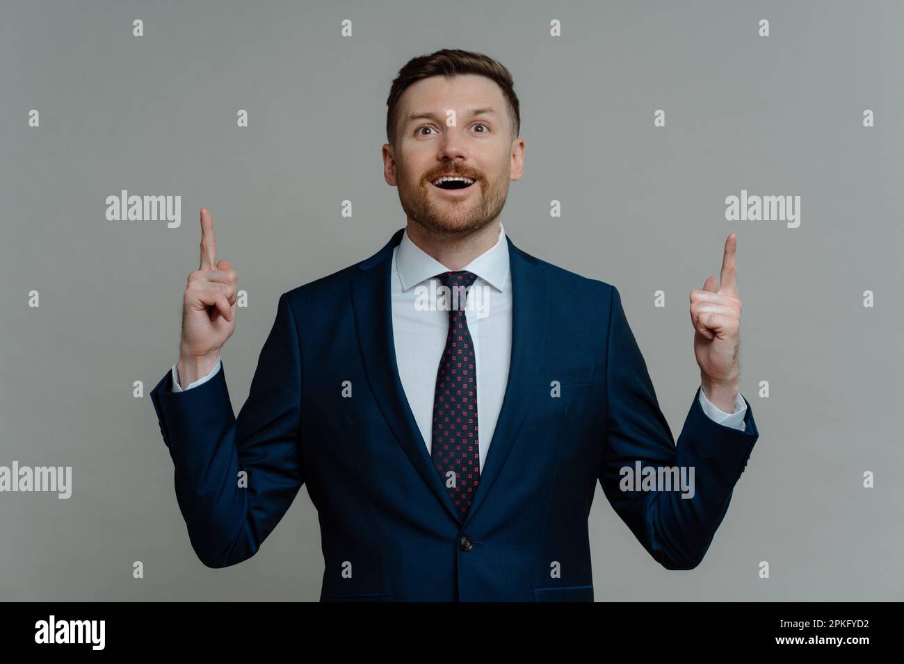 Shocked amazed business leader in suit pointing up with his fingers and ...