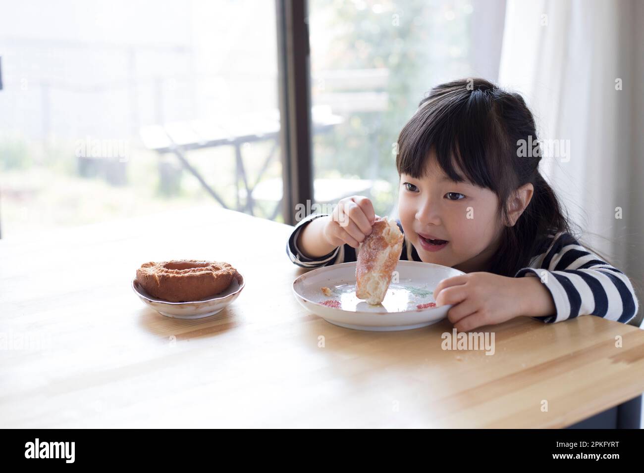 Girl eating a snack doughnut Stock Photo - Alamy