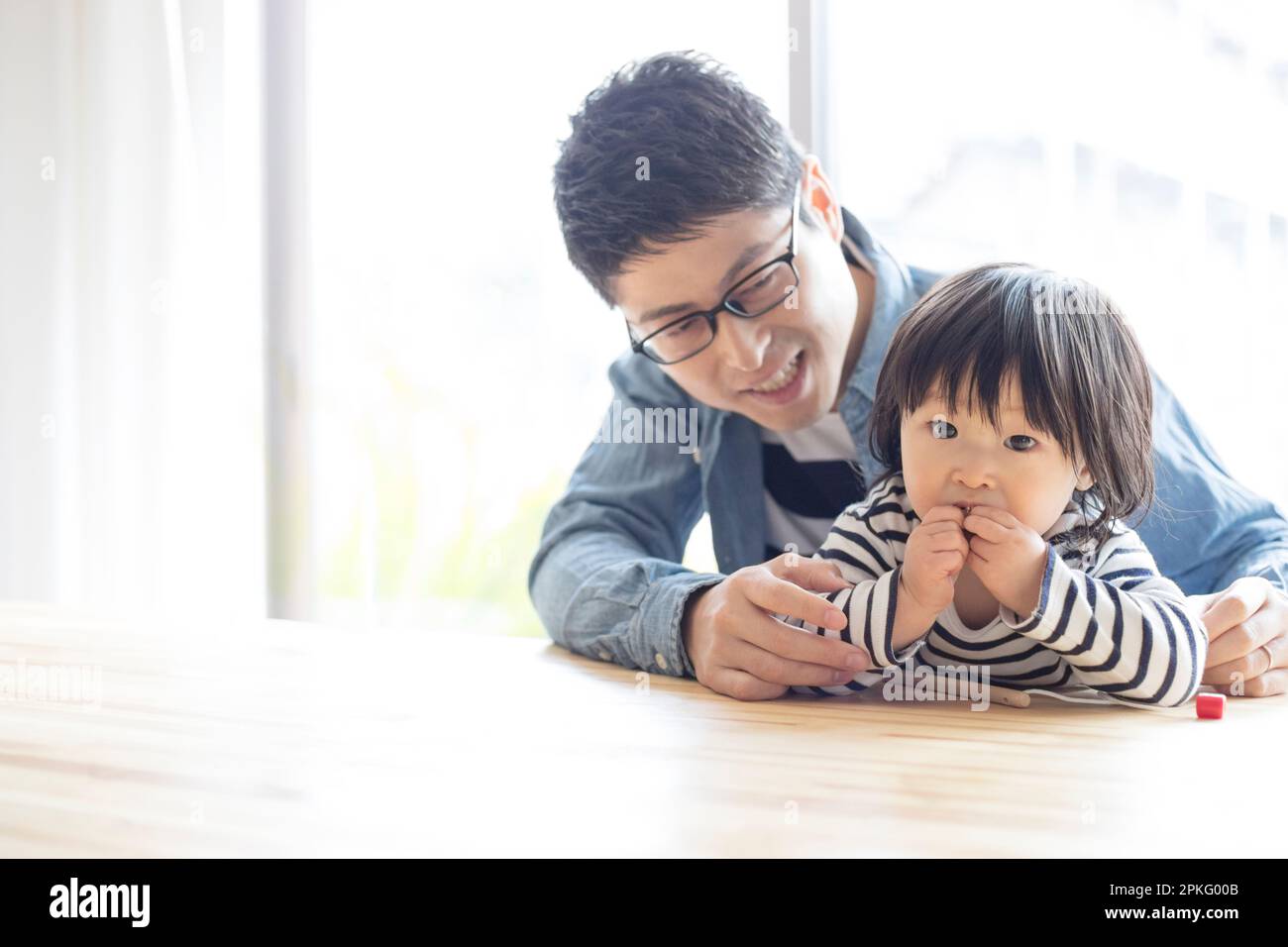 A baby sitting on her father's lap and eating a snack Stock Photo - Alamy