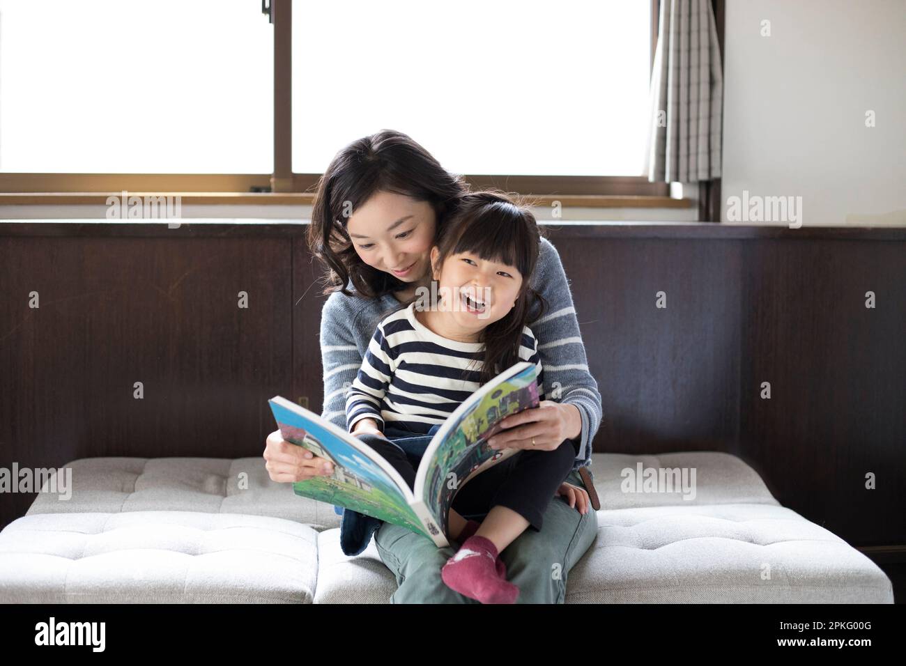 A girl sitting on her mother's lap and having a book read to her Stock ...