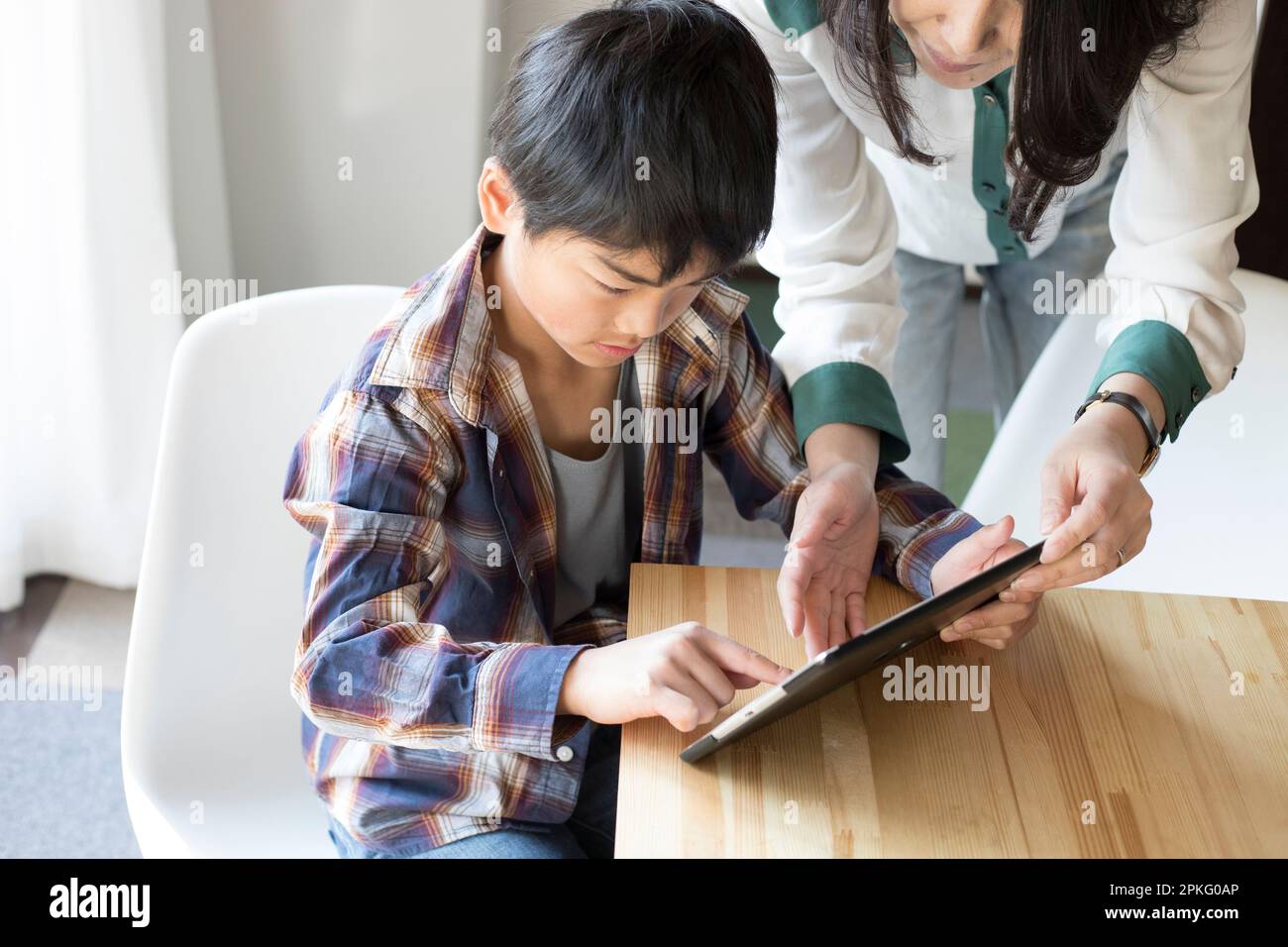 A boy being taught how to use a tablet by his mother Stock Photo - Alamy