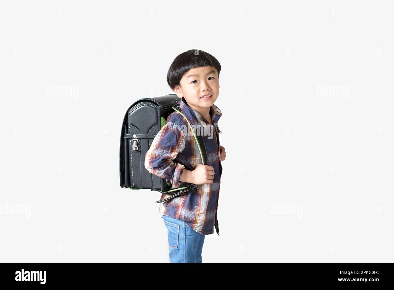 Elementary school boy standing in front of a white wall with his school ...
