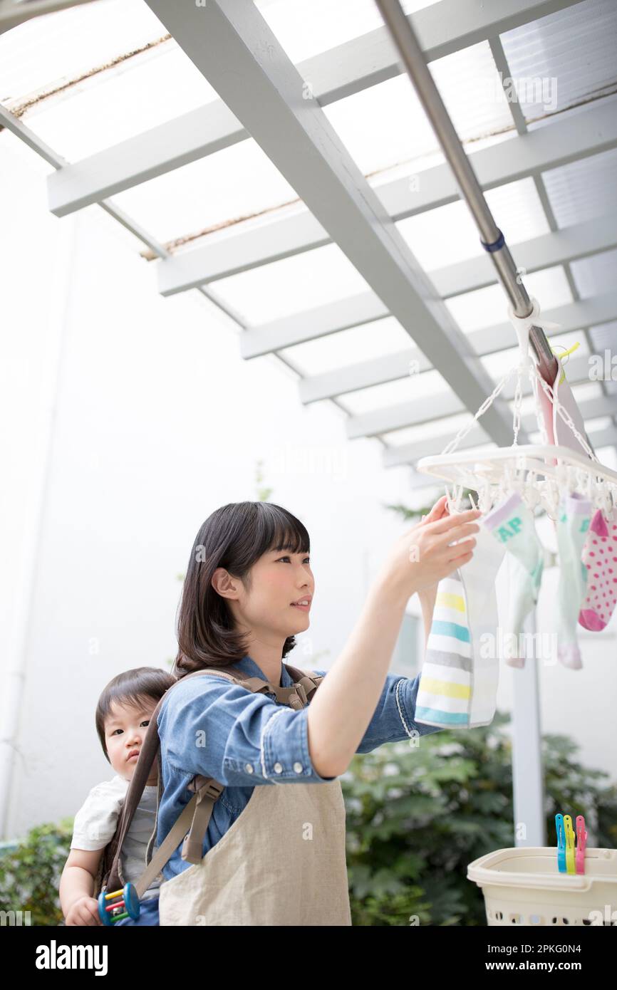 Mother drying laundry with child on back Stock Photo - Alamy