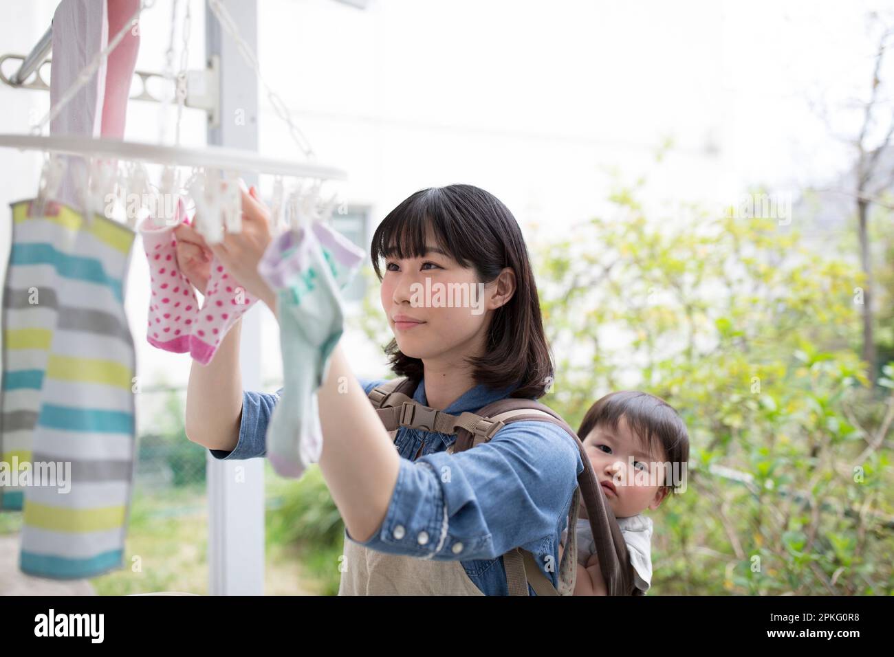 A mother drying laundry with her child on her back Stock Photo - Alamy