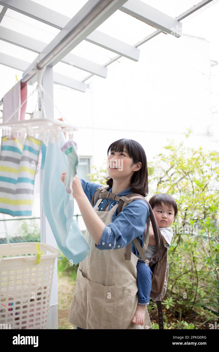 Mother drying laundry with child on back Stock Photo - Alamy
