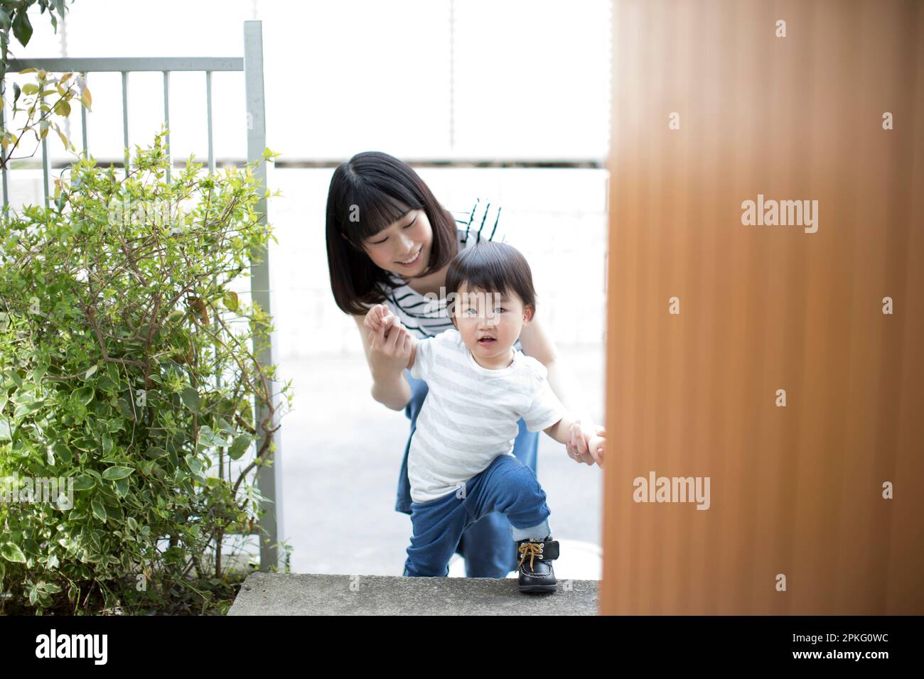 Mother and toddler trying to enter house holding hands Stock Photo - Alamy