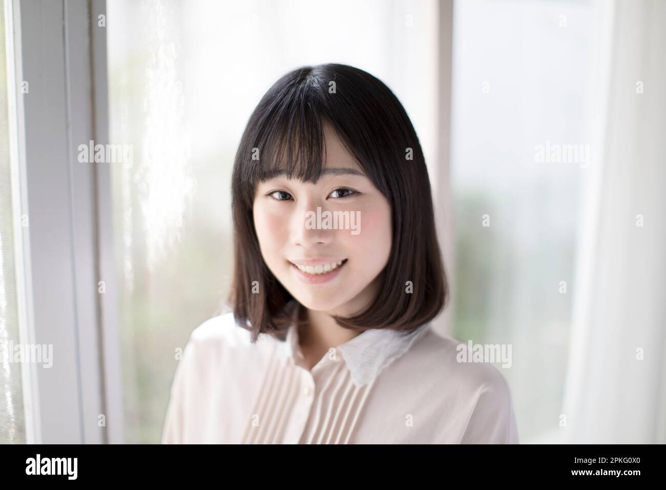 Woman Smiling By Window Stock Photo - Alamy