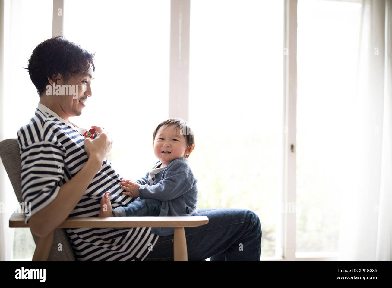 Baby playing sitting on father's lap Stock Photo - Alamy