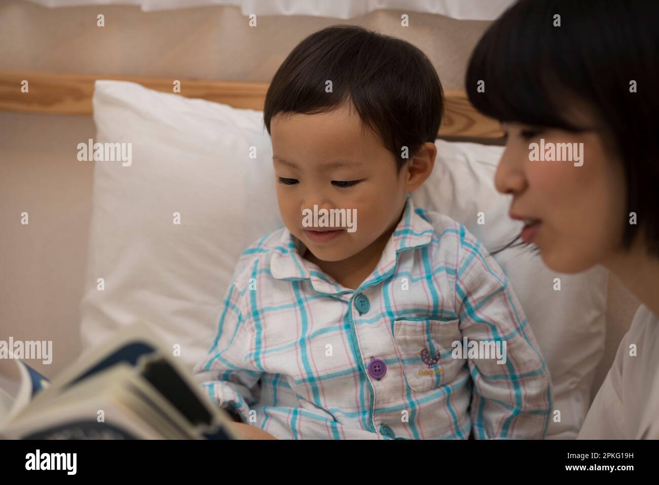 Boy having picture book read to him by his mother in bed Stock Photo ...