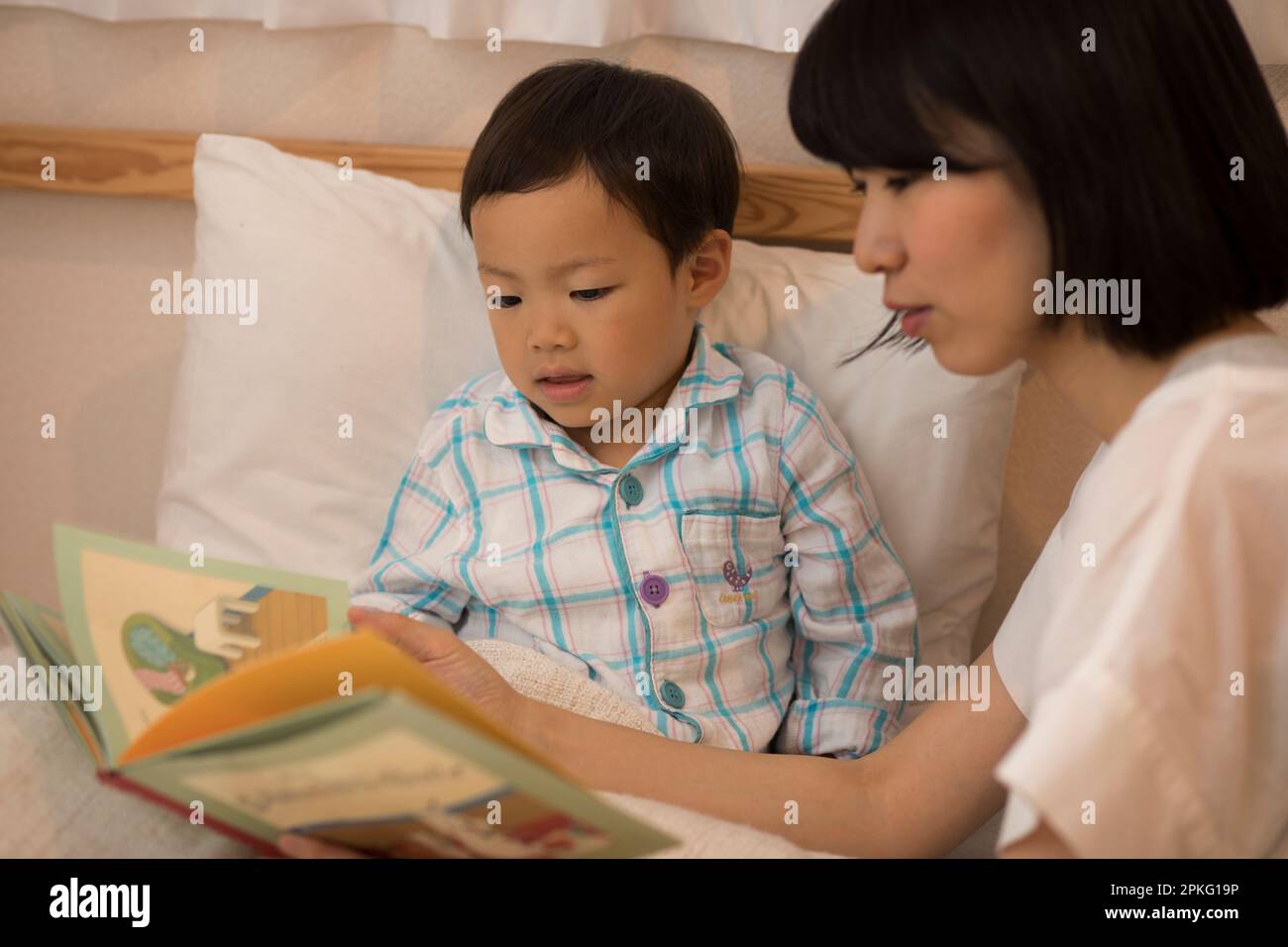 Boy in bed being read to by his mother Stock Photo - Alamy