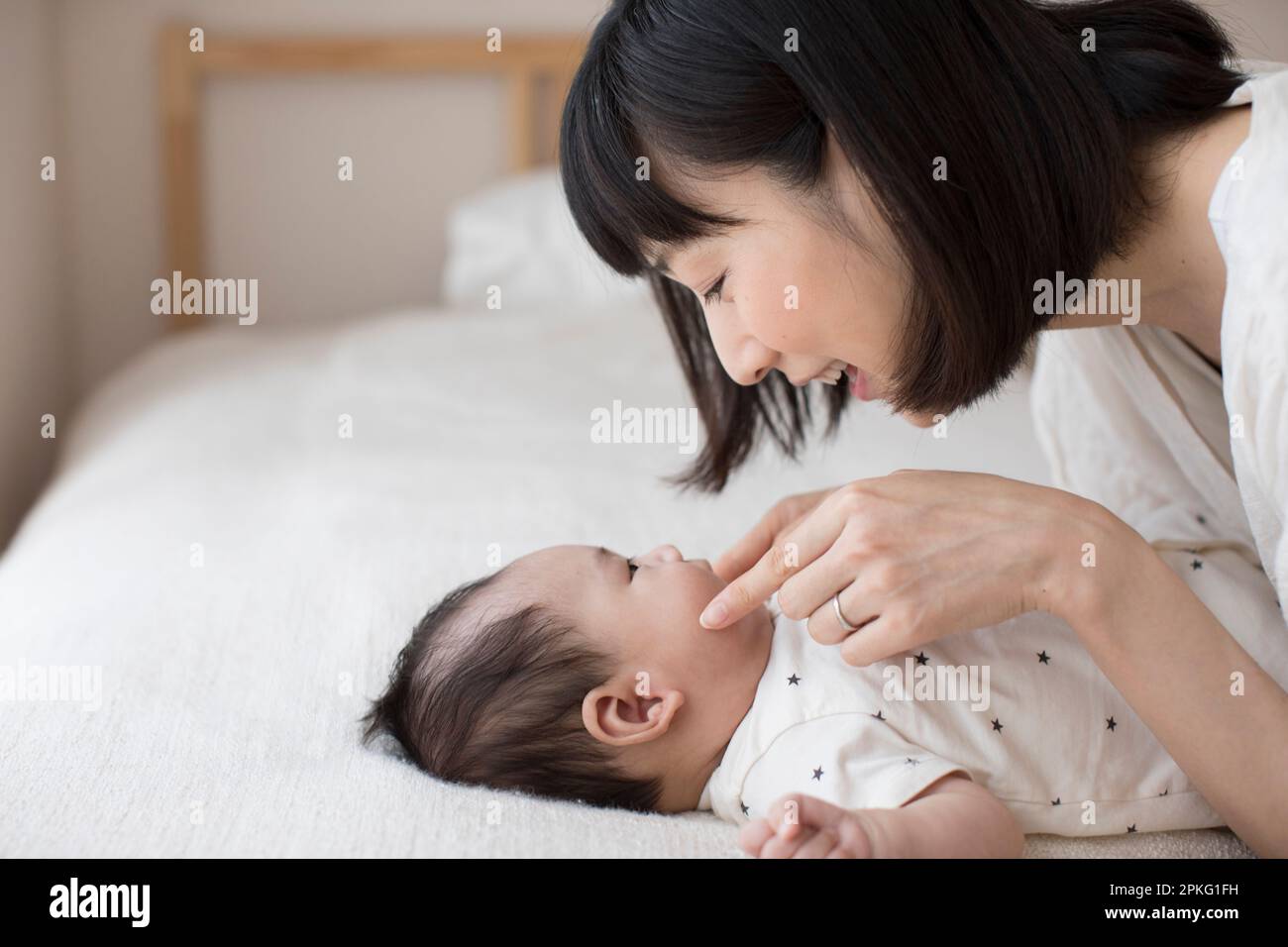 Mother cradling baby lying on back on bed Stock Photo - Alamy