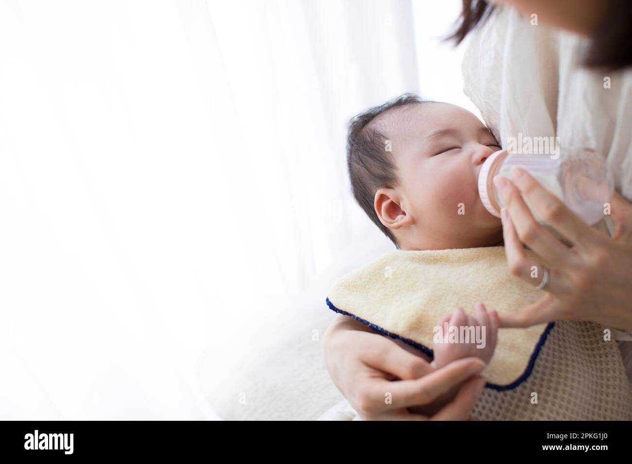 Baby sleeping in mother's arms, drinking milk and holding mother's ...