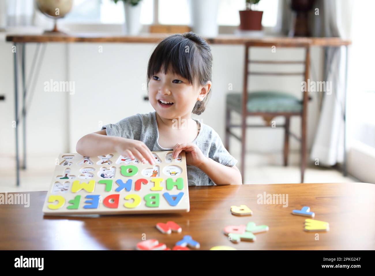 Girl playing with alphabet puzzle Stock Photo - Alamy