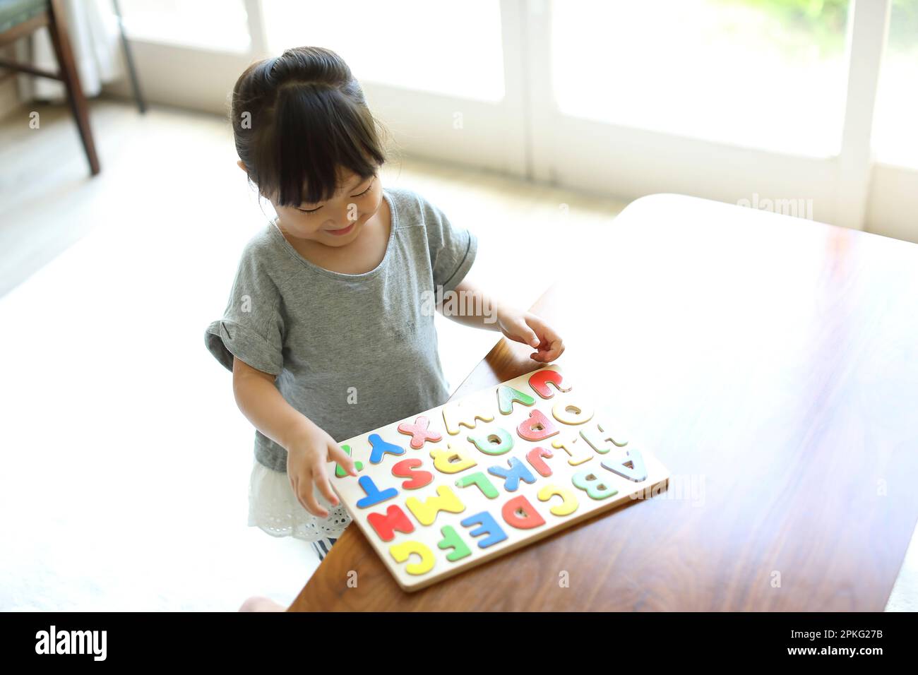 Girl doing alphabet puzzle Stock Photo - Alamy