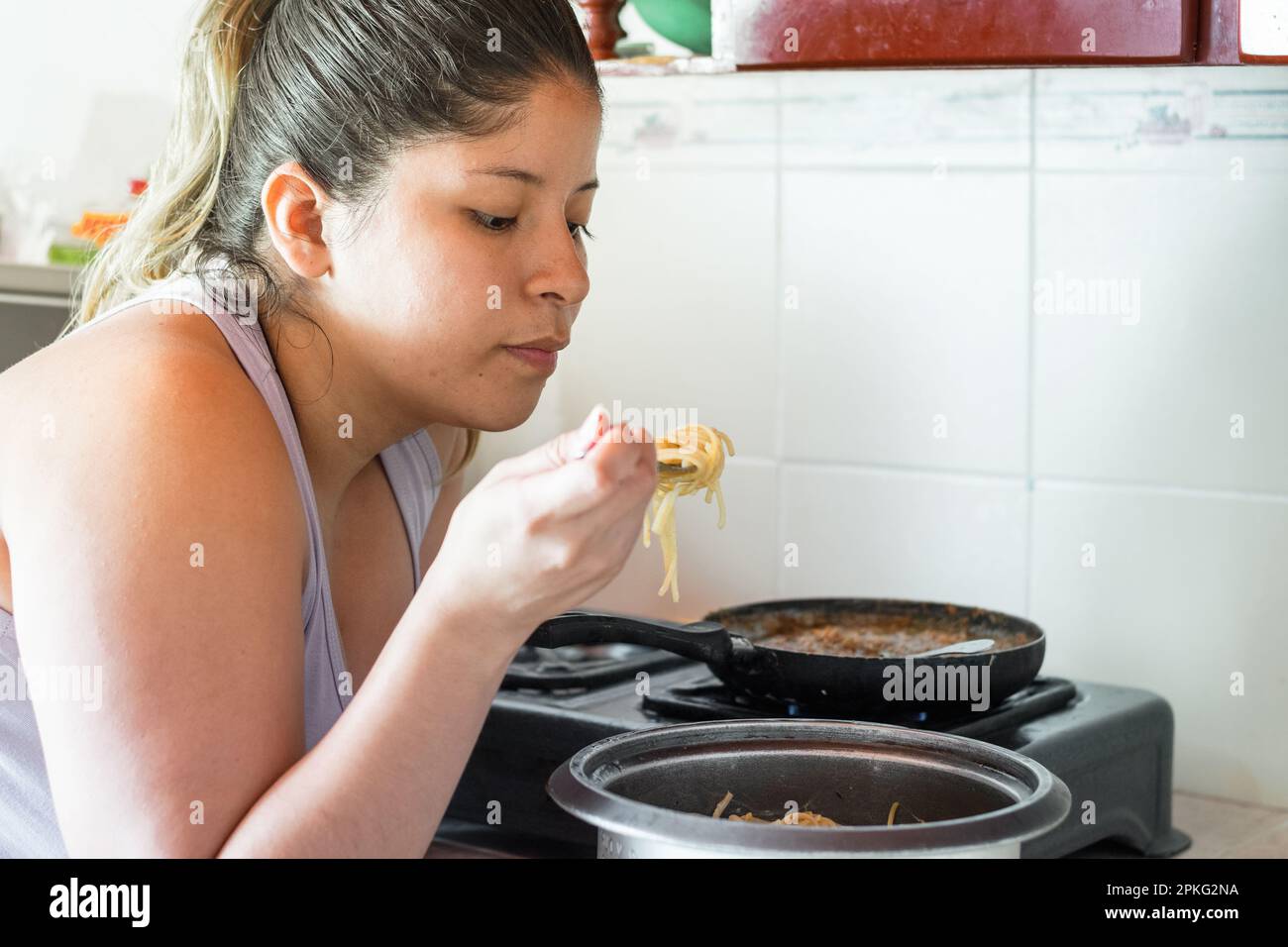 young woman testing with a spoon how cooked the spaghetti was Stock ...
