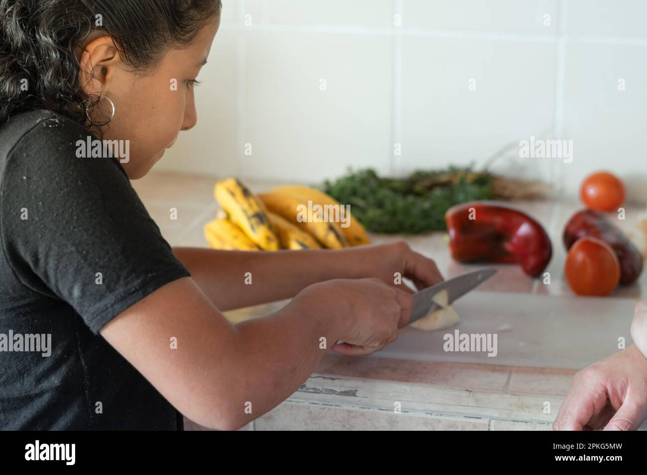 little latin girl, splitting an onion with a knife, learning to cook at ...