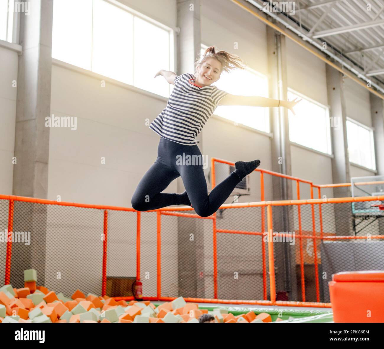 Pretty girl in trampoline park jumping with split and smiling. Happy ...