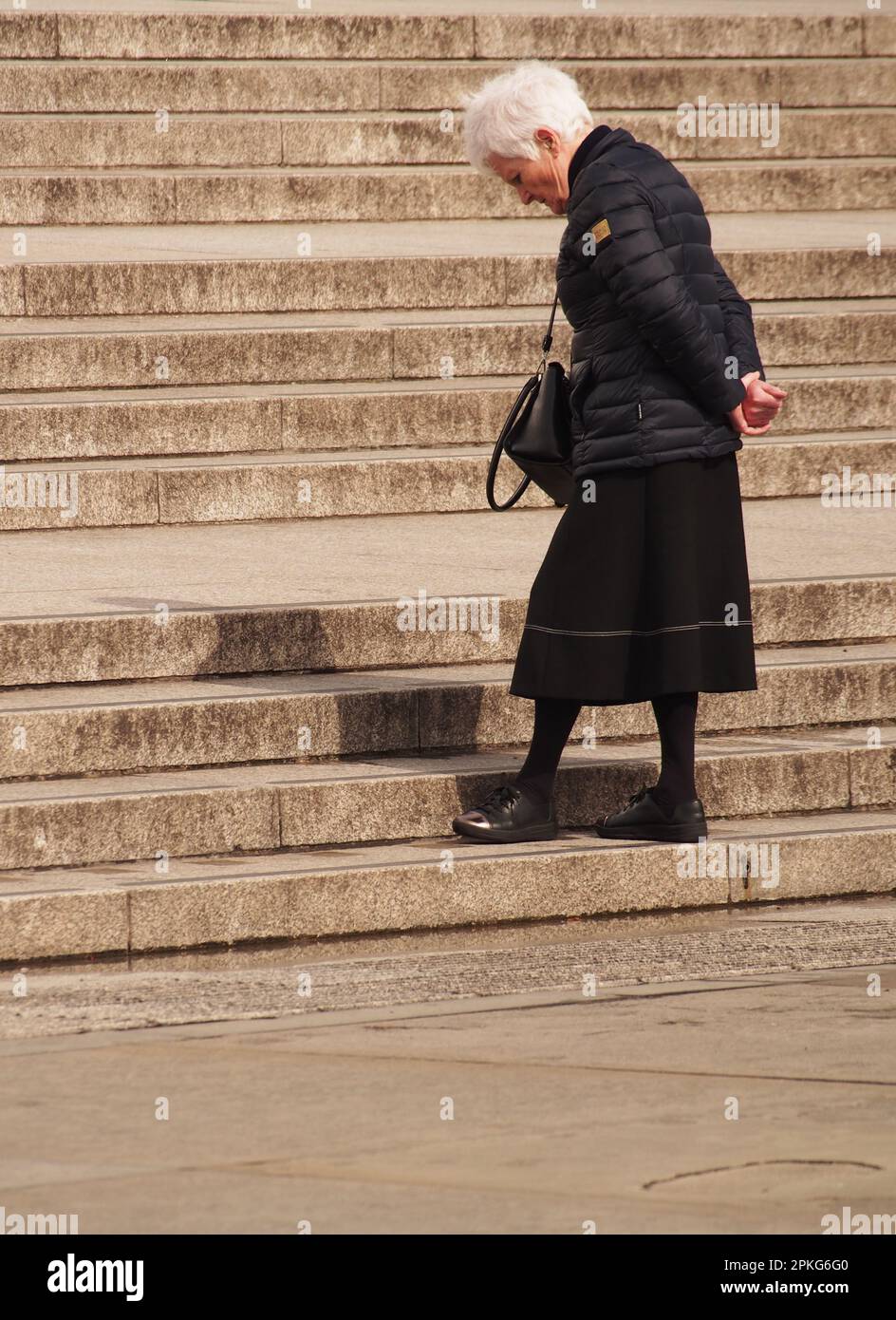 An older woman 60+ standing on the bottom stone step in Trafalgar ...