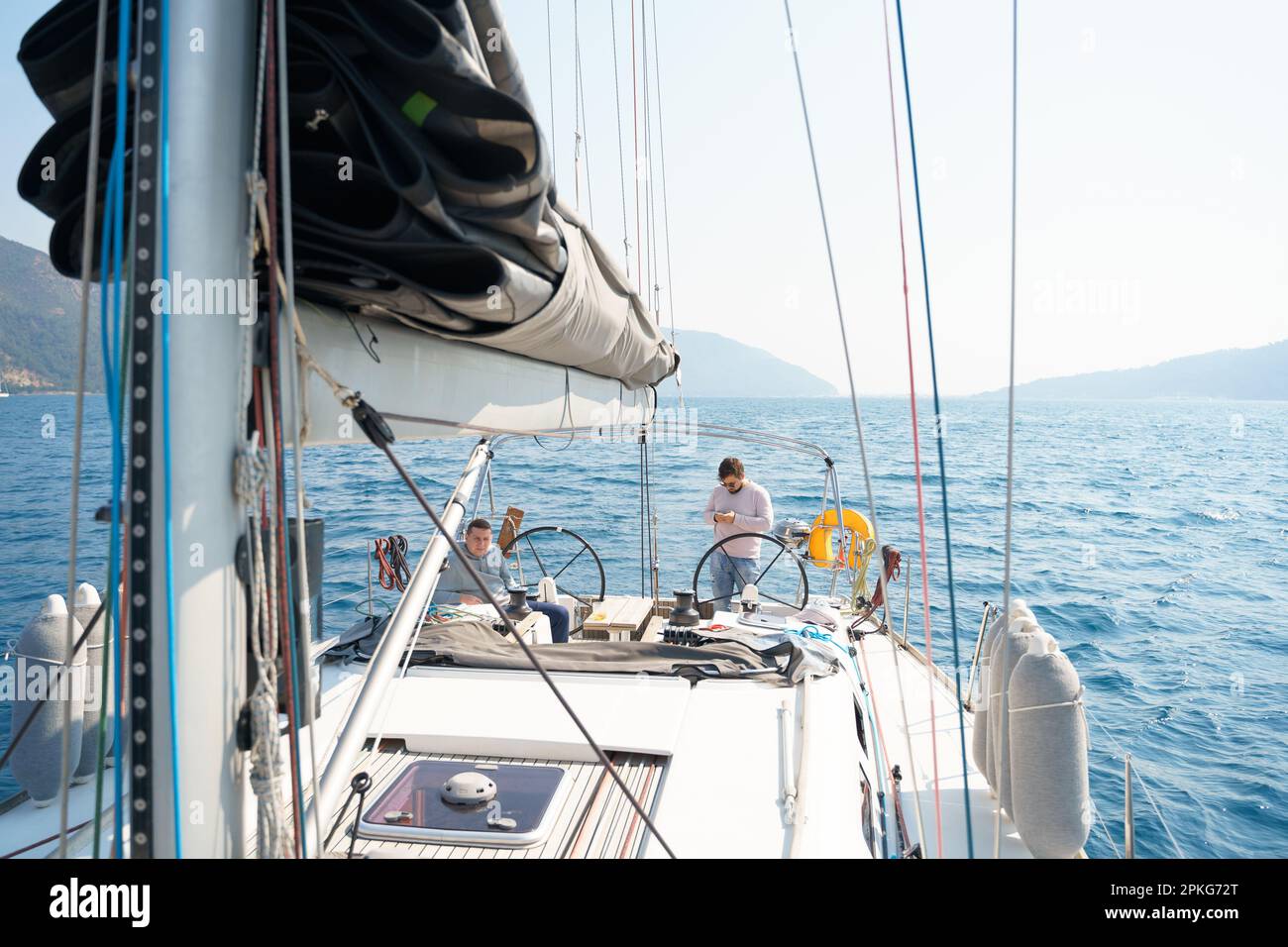 Businessman, owner with mobile phone at steering wheel in voyage sail ...