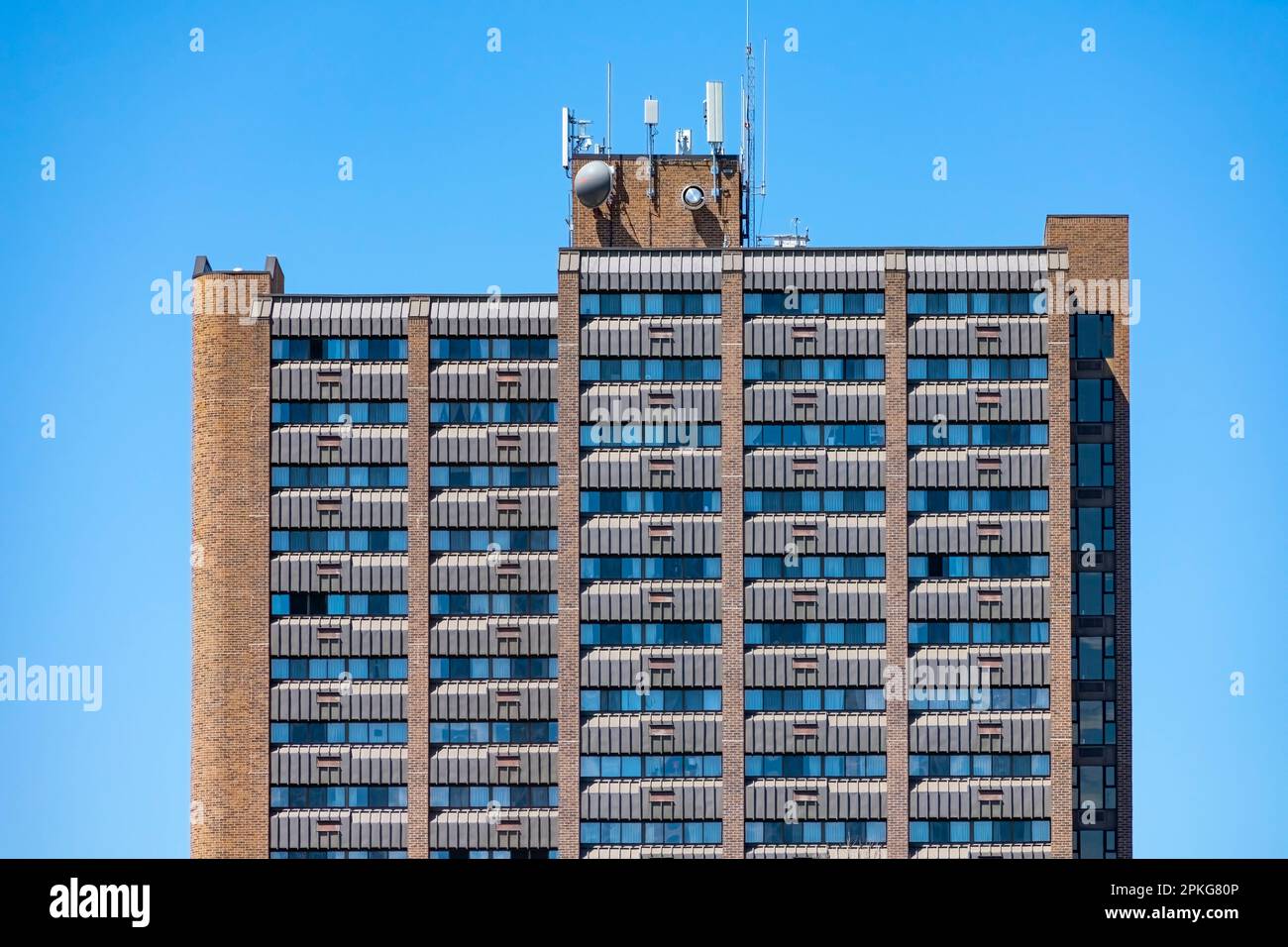 Horizontal shot of a high-rise apartment building with communications equipment on the roof ...