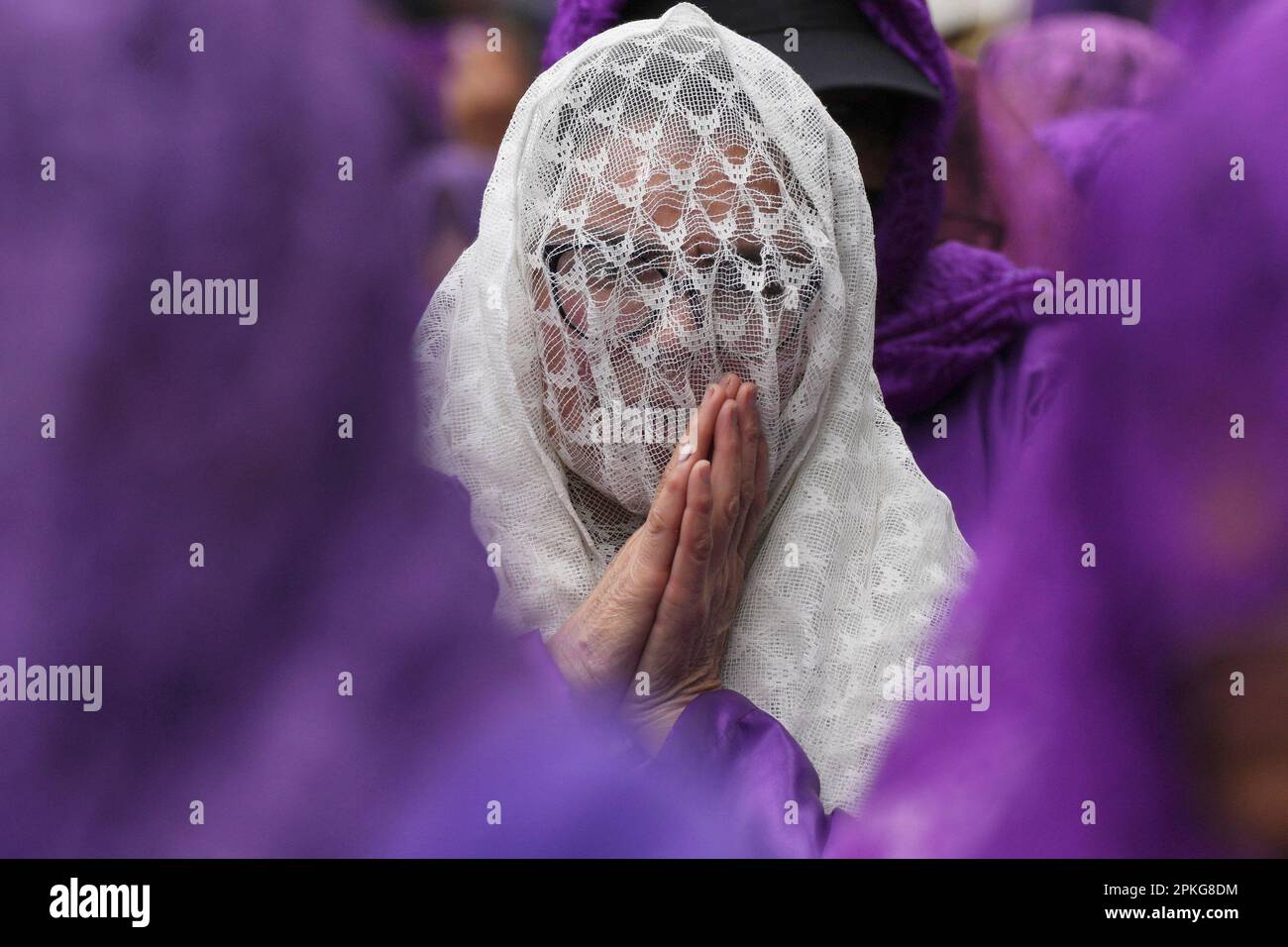 A woman, wearing a veil, holds her hands in prayer during the "Jesus ...