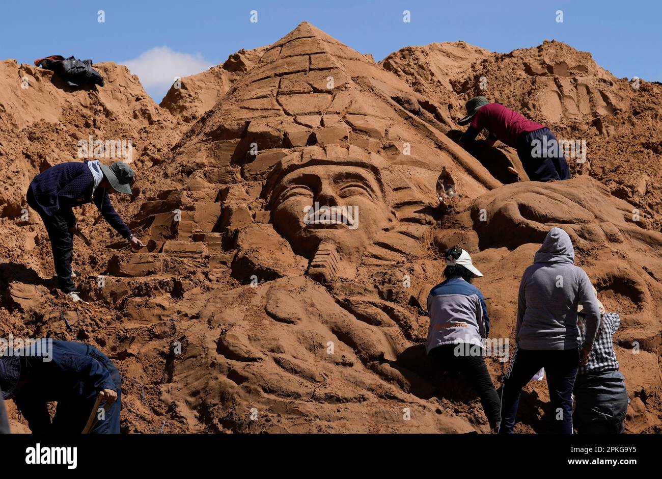 Artists work on a sand sculpture depicting a pharaoh and a pyramid, as ...