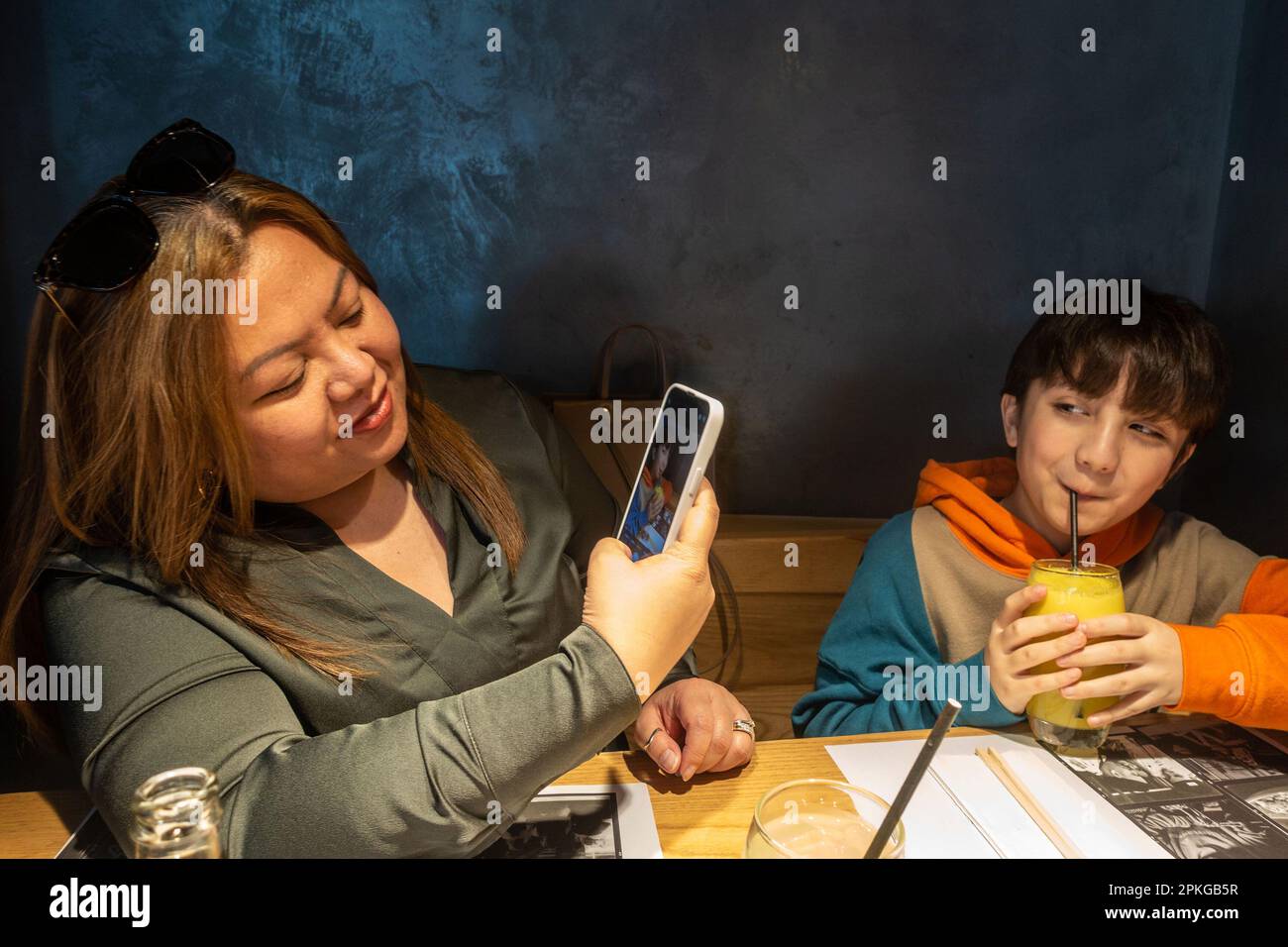 A mum takes a photo of her son with her mobile phone while on a meal ...