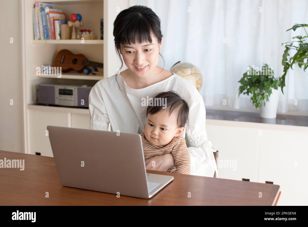 Mother and baby watching computer together in living room Stock Photo ...