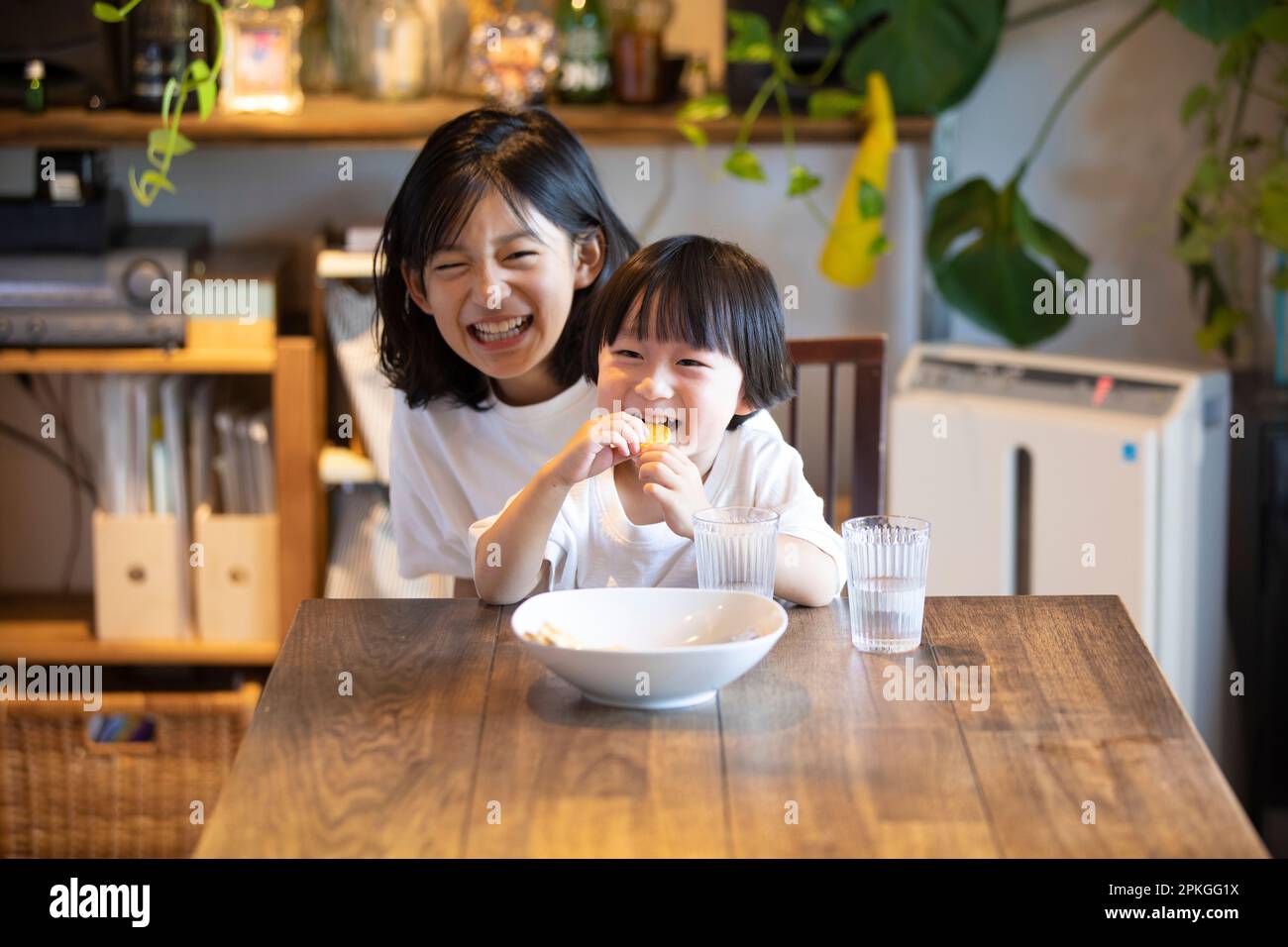 Boy sitting on his sister's lap and smiling while eating a snack Stock ...