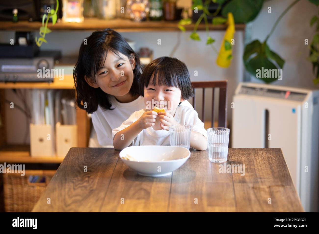 Boy sitting on his sister's lap and smiling while eating a snack Stock ...