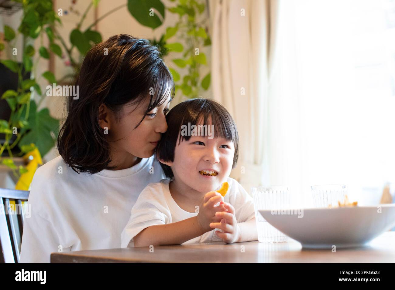Boy smiling while sitting on his sister's lap and eating a snack Stock ...