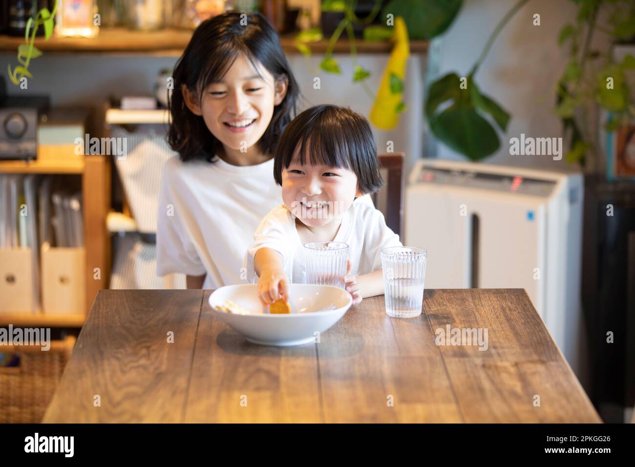 Boy sitting on his sister's lap and smiling while eating a snack Stock ...