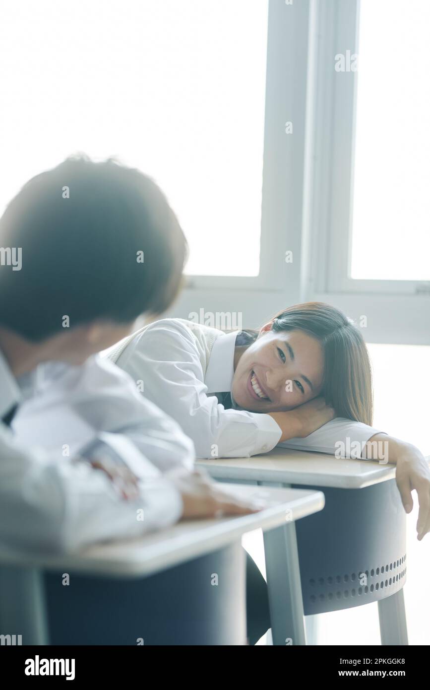 Male and female high school students chatting in a classroom during ...