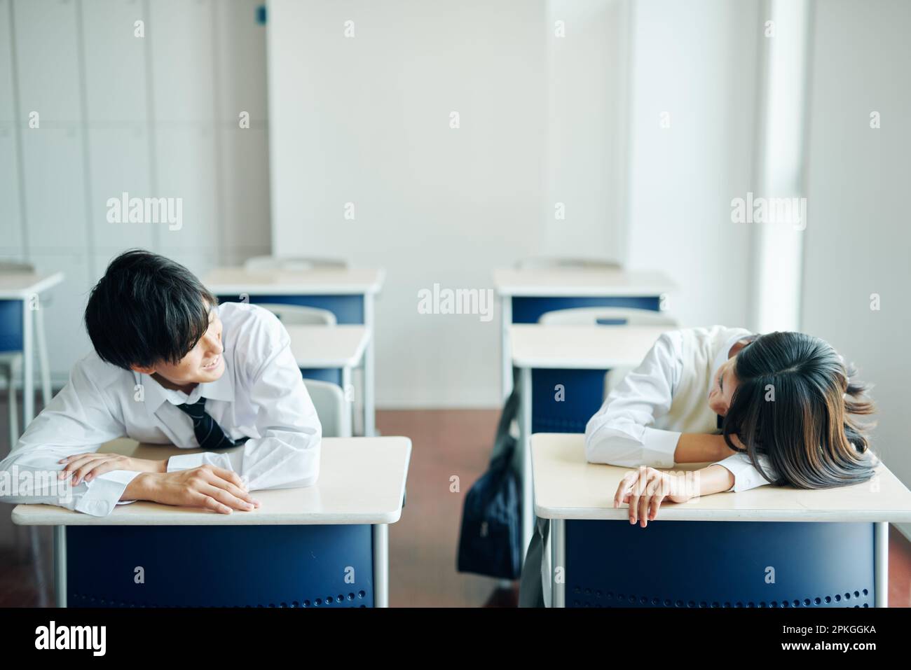 A male and female high school student chatting in a classroom during ...