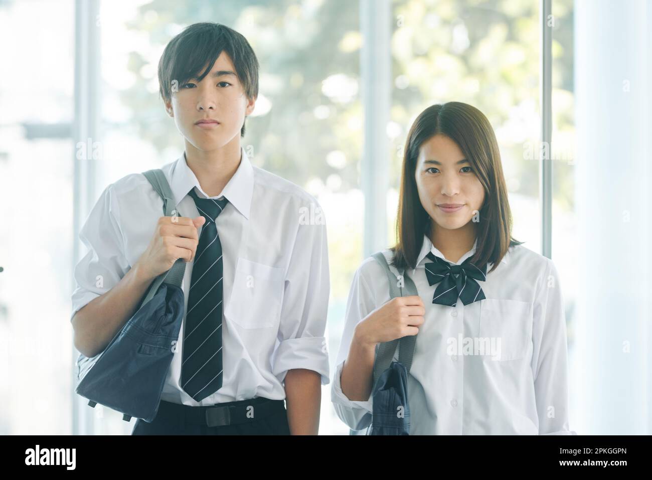 High school students of both sexes standing in a line with their bags ...