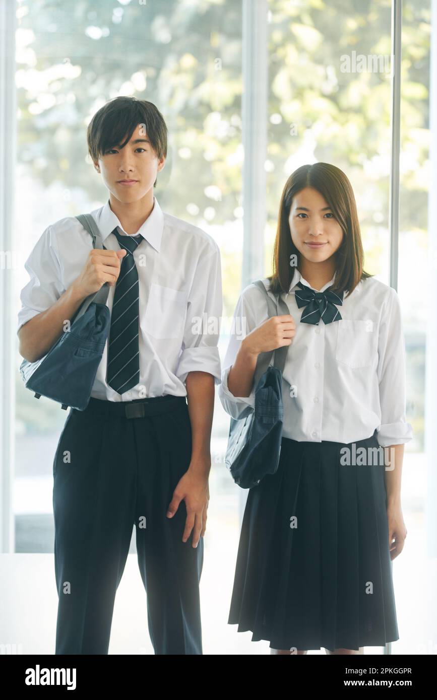 Male and female high school students standing in a row with their bags ...