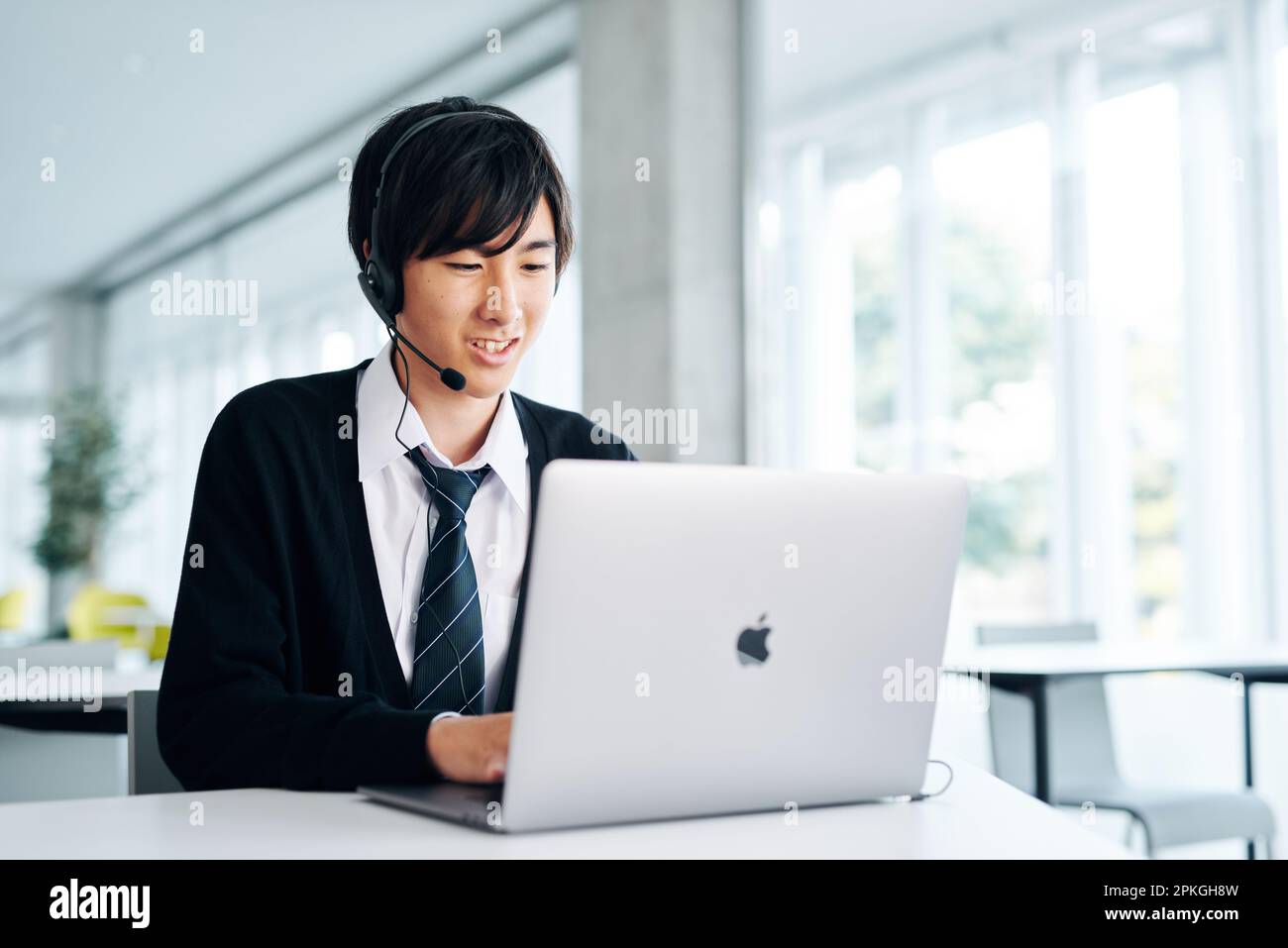 A male high school student taking an online class at a cram school ...