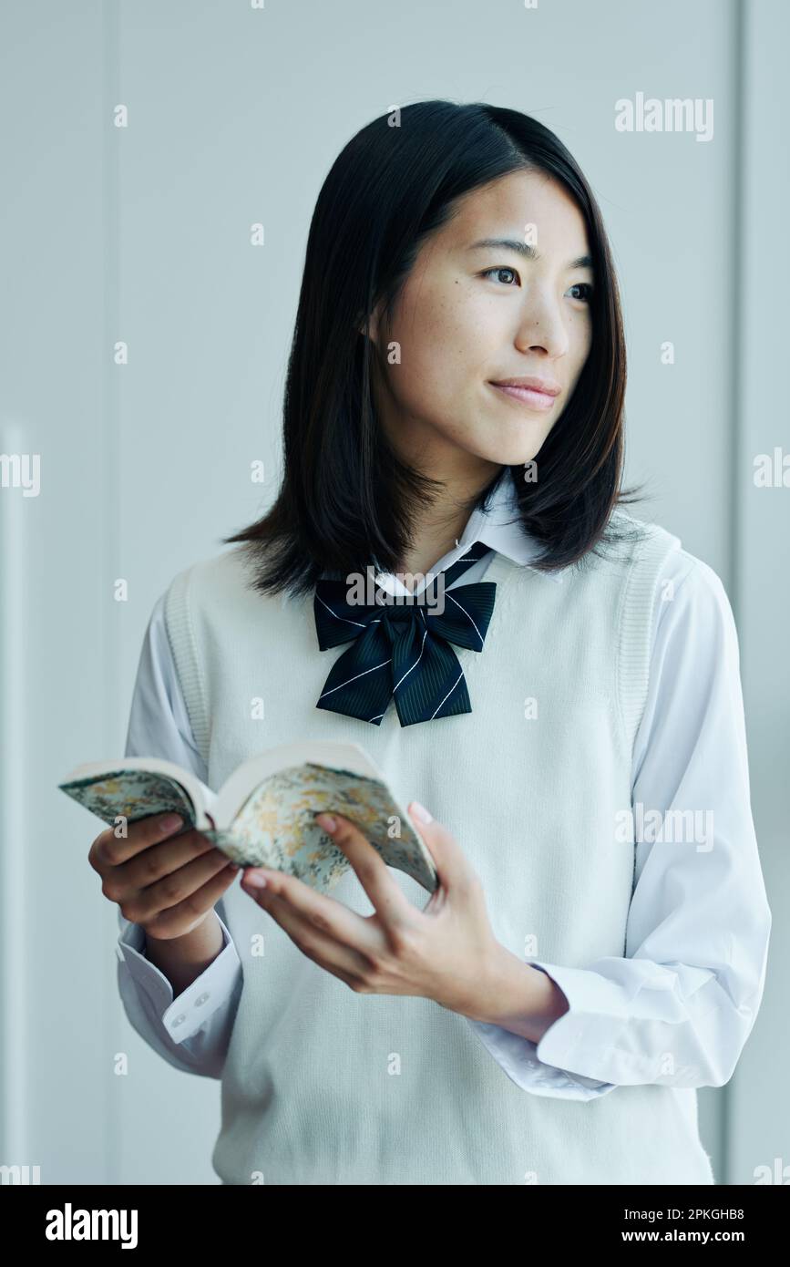 Female high school student reading a book by the window Stock Photo - Alamy