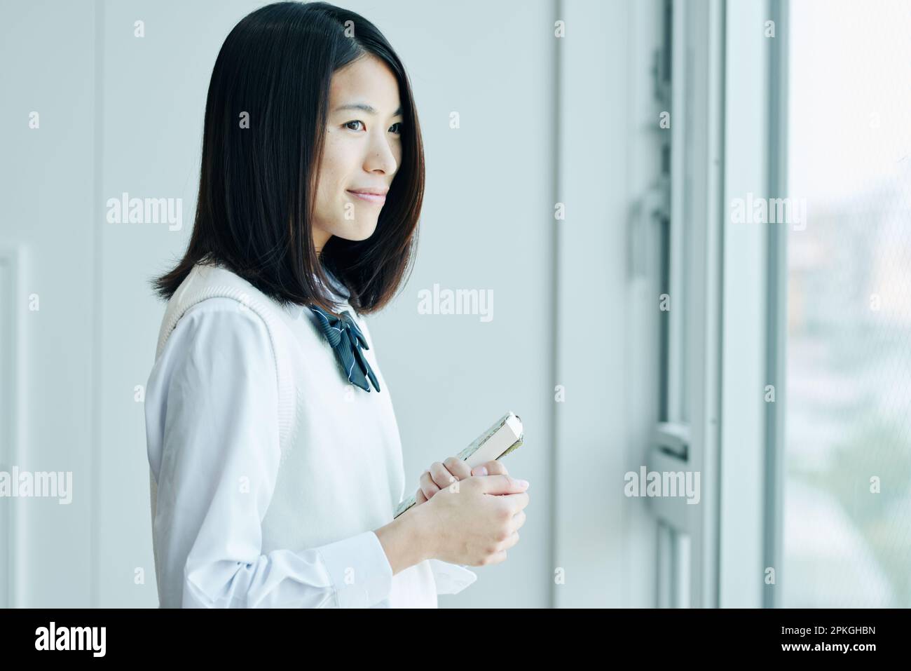High school student holding a book by the window Stock Photo - Alamy
