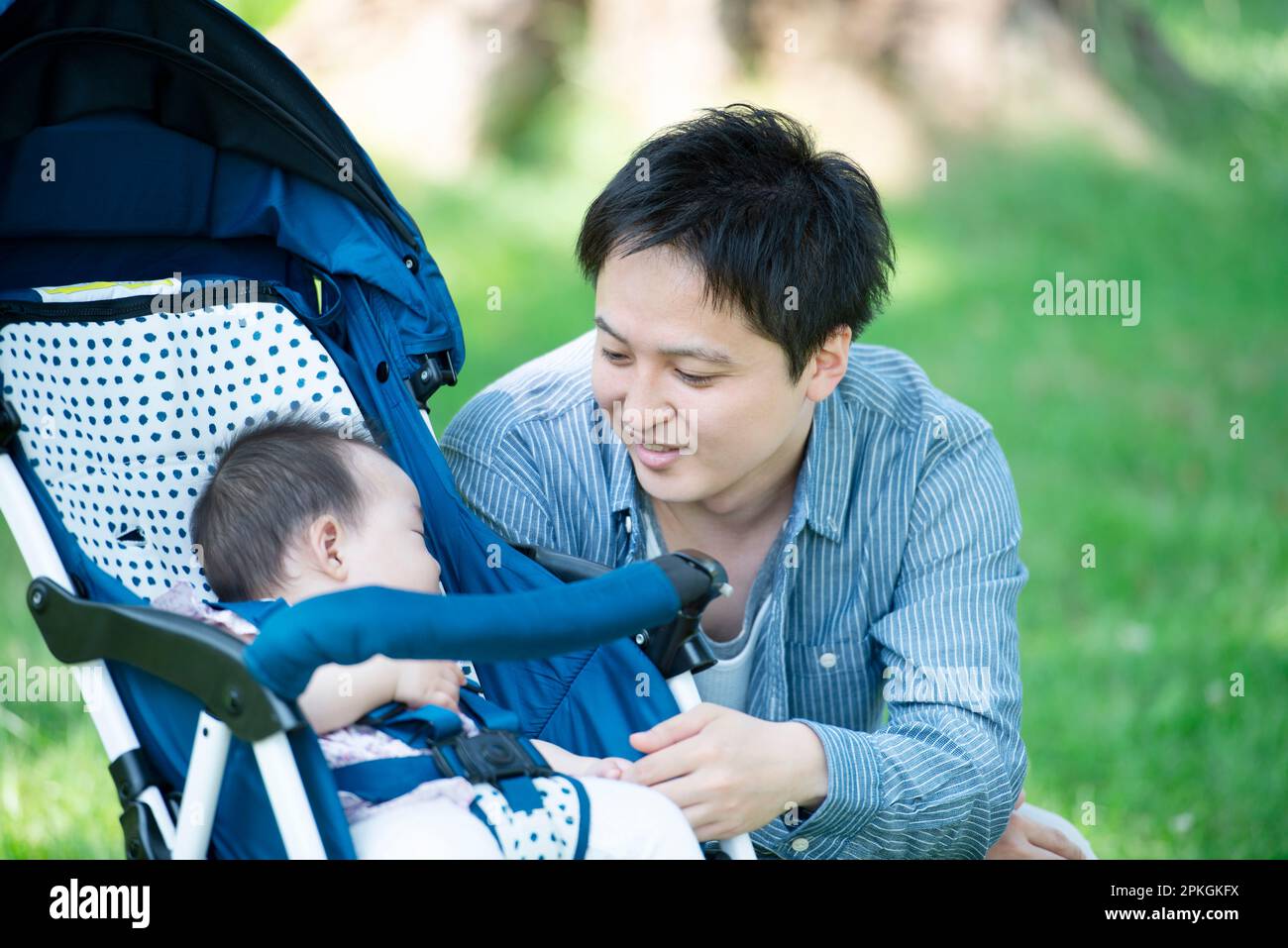 A father watches his baby riding in a stroller Stock Photo - Alamy