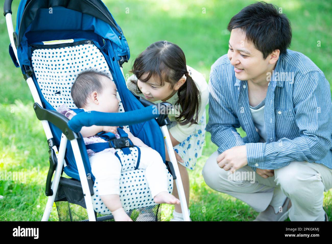 Parent and child watching baby in stroller Stock Photo - Alamy