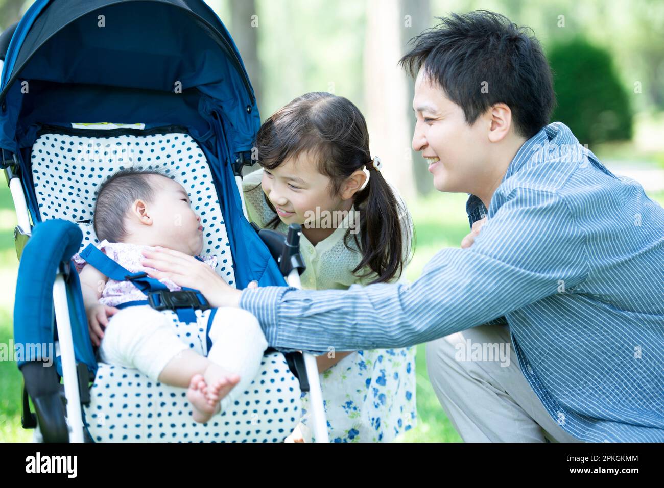 Parent and child watching baby in stroller Stock Photo - Alamy