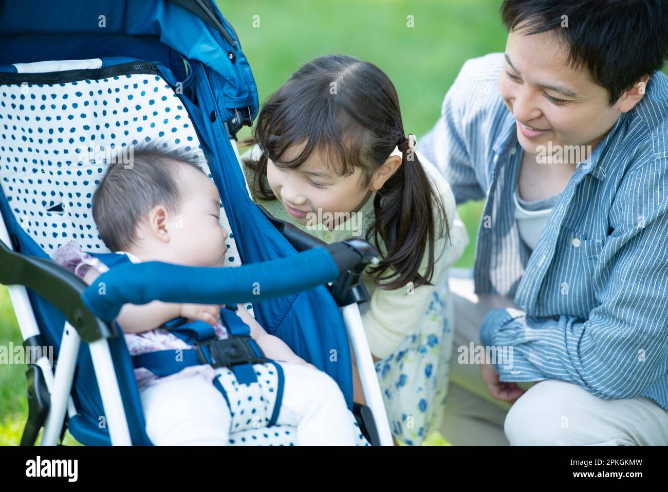 Parent and child watching baby in stroller Stock Photo - Alamy