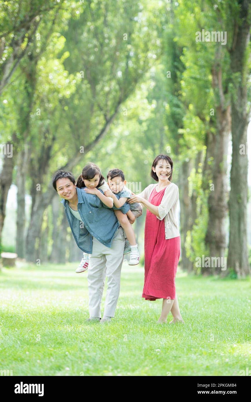 A parent and child carrying a baby on their back at a row of poplar ...
