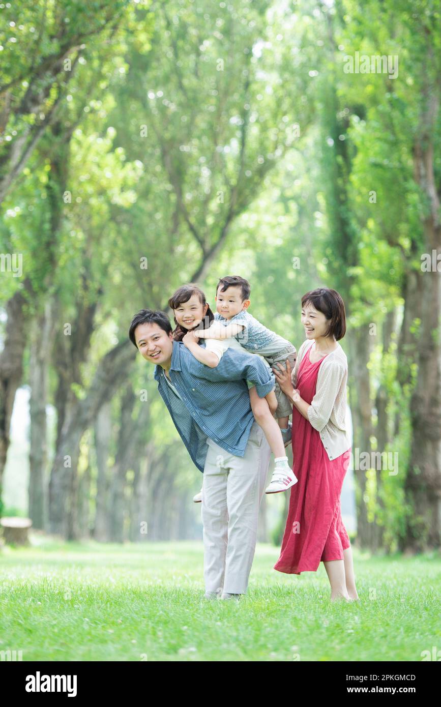 A parent and a child carrying a baby on his back in a row of poplar ...