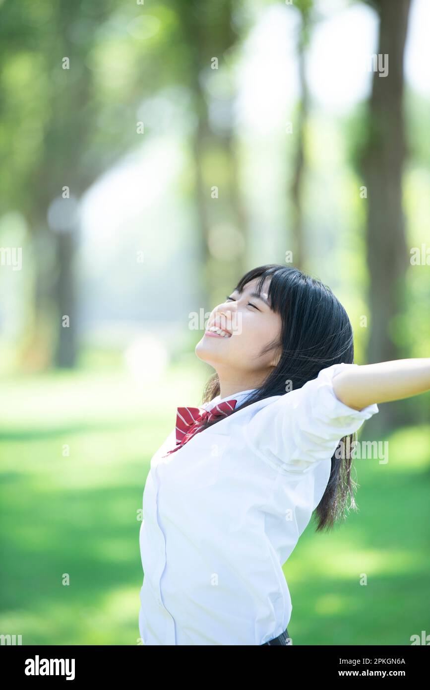 Female student spreading her arms out in front of a row of poplar trees ...